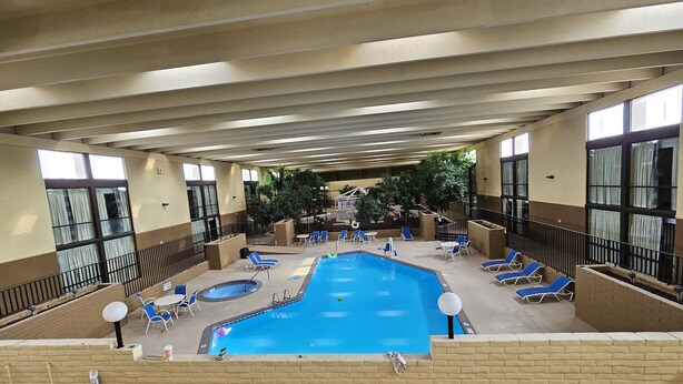 Piscina interna com água azul, rodeada por cadeiras de descanso e mesas.