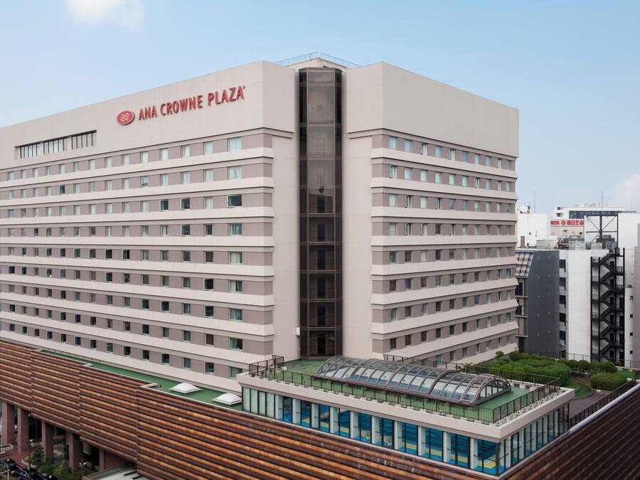 Um hotel de vários andares com uma placa chamativa que diz 'ANA CROWNE PLAZA'.