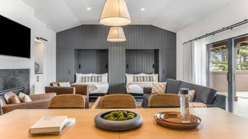 Uma sala de estar moderna com uma grande mesa de madeira, dois sofás e uma TV fixada na parede.