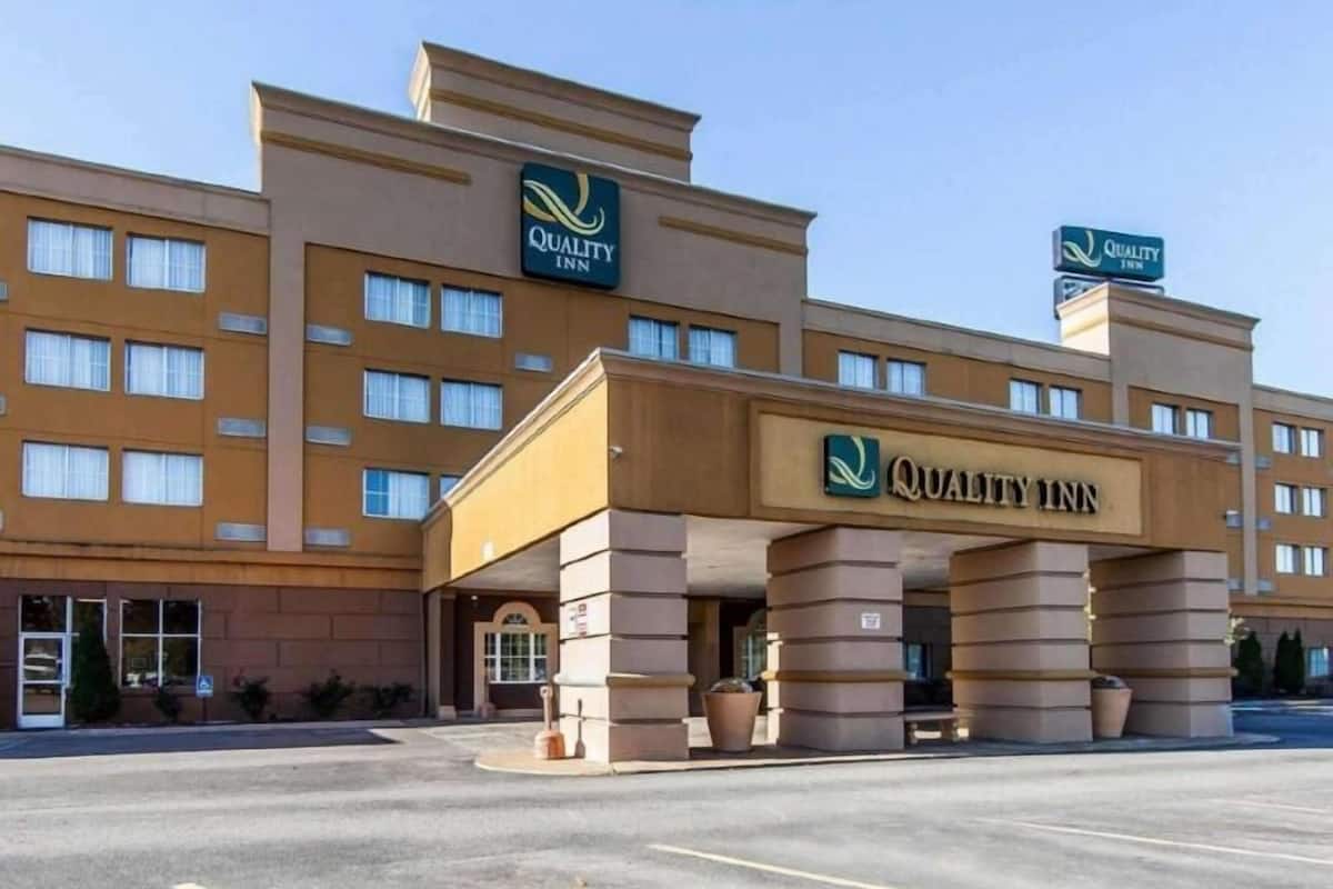 Um hotel com um grande letreiro de 'Quality Inn', entrada central e estacionamento.