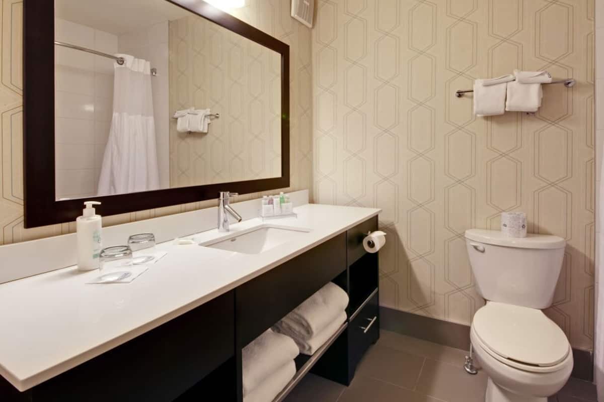 Uma casa de banho moderna com um espelho grande, duas pias, uma sanita e um porta-toalhas.