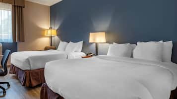 Quarto de hotel com duas camas, uma escrivaninha, uma cadeira e duas luminárias.