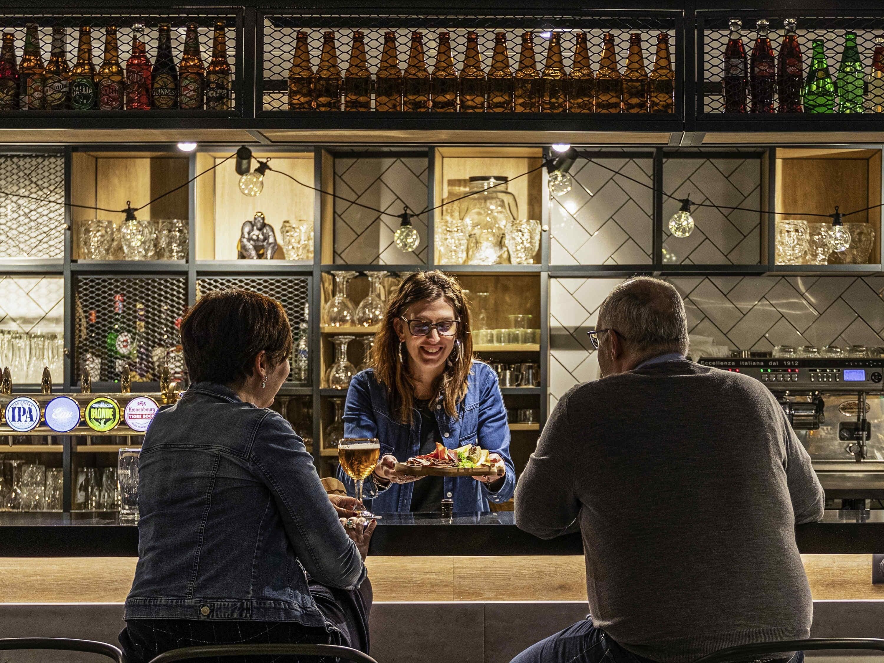 Um balcão de bar com prateleiras cheias de garrafas e copos.
