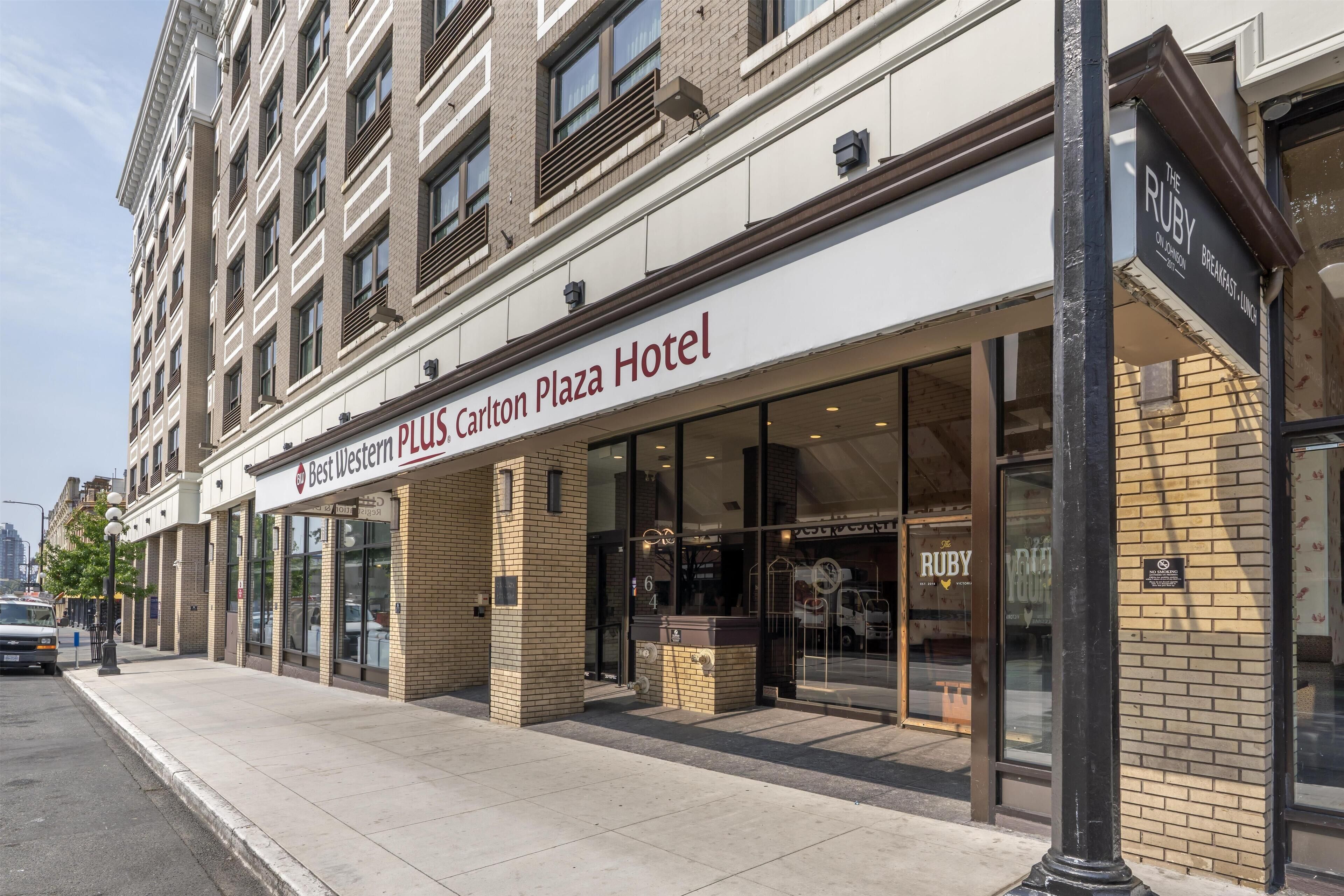 Hotel Carlton Plaza, com entrada acessível, sinalização visível para o Ruby Breakfast Lounge e fachada de tijolos.