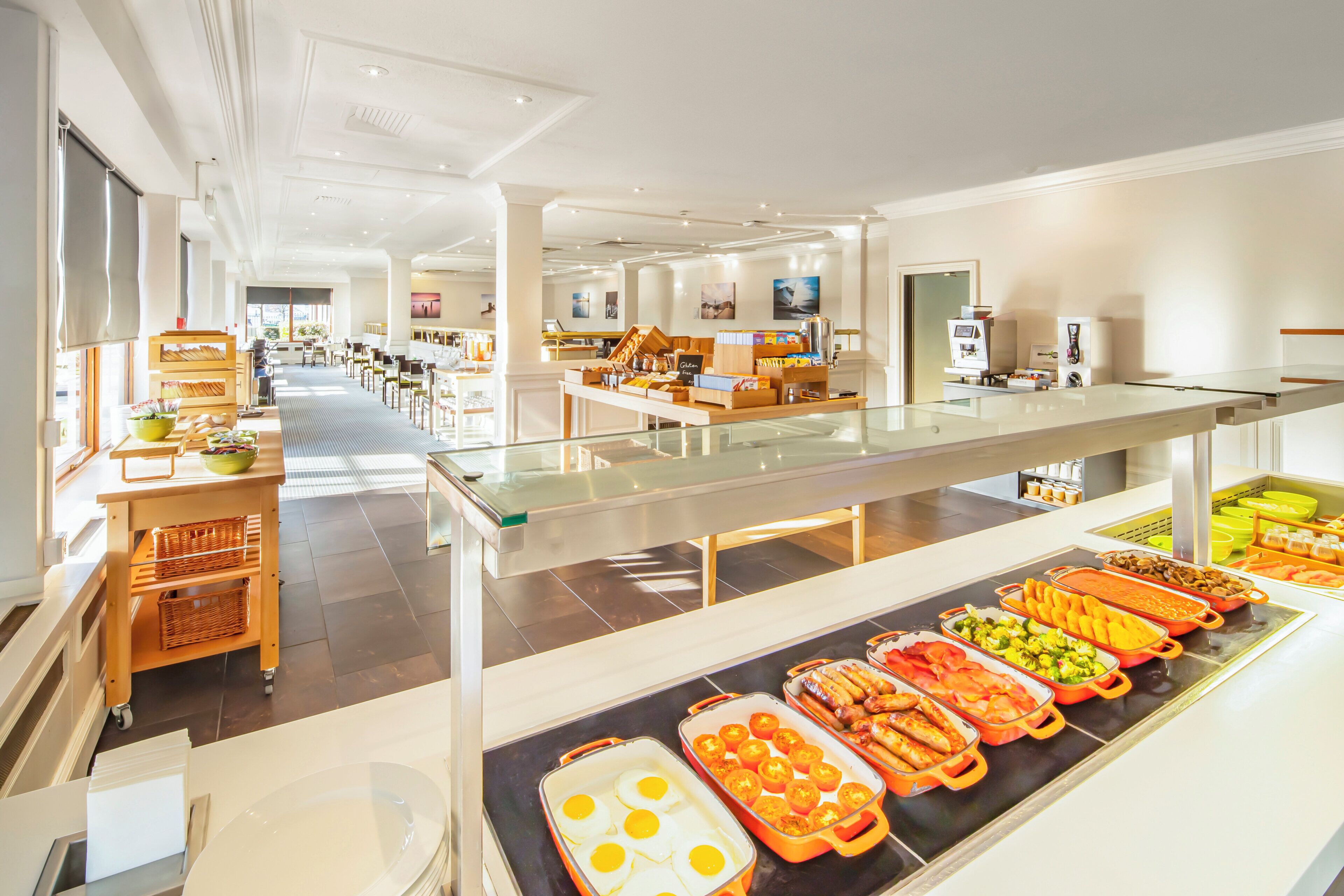 Espaço de buffet com diversas opções de comida e área de estar com mesas e cadeiras.