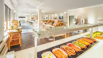 Espaço de buffet com diversas opções de comida e área de estar com mesas e cadeiras.
