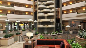 Um hall de hotel com vários níveis, átrio central, diversos andares e diferentes espaços de estar.