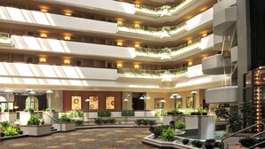 Um átrio de hotel com vários níveis, varandas, plantas e obras de arte nas paredes.