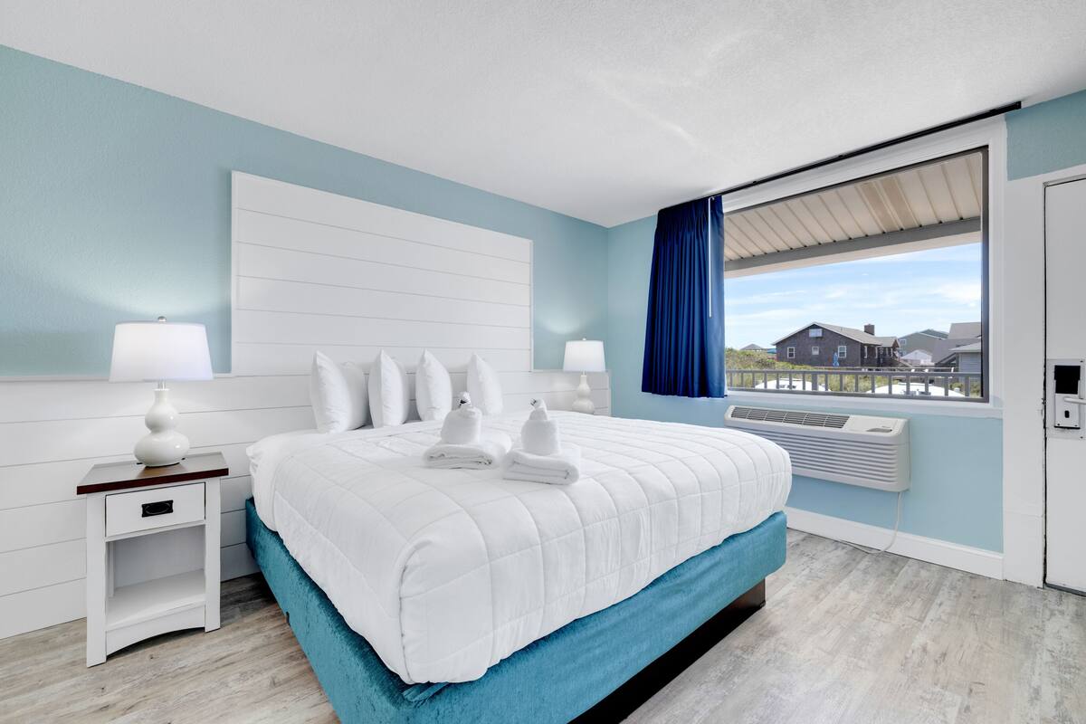 Quarto com cama, duas mesas de cabeceira, janela com vista e ventilador de teto.