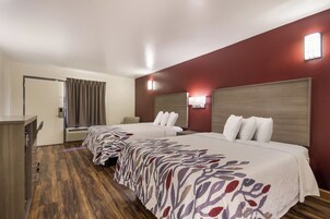 Quarto de hotel com duas camas, uma escrivaninha e um guarda-roupa.