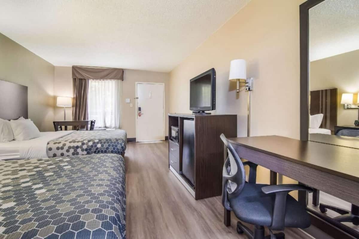 Quarto de hotel com duas camas, uma escrivaninha, uma televisão e um espelho.