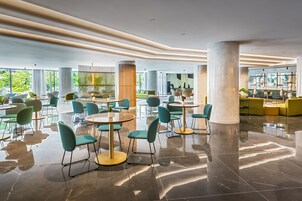 Um hall amplo com mobiliário moderno, grandes janelas e piso lustroso.