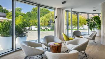 Quarto de hotel moderno com grandes janelas, assentos confortáveis e vista para o exterior.