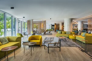 Um hall amplo com grandes janelas, mobiliário moderno e uma área de estar central.
