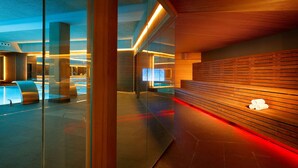 Uma área de spa moderna com paredes de vidro, painéis de madeira e o letreiro de uma sauna.