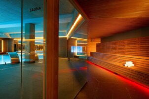 Uma área de spa moderna com paredes de vidro, painéis de madeira e o letreiro de uma sauna.