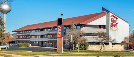 Hotel Red Roof Plus com design moderno, apresentando telhado vermelho e fachada de tijolos.