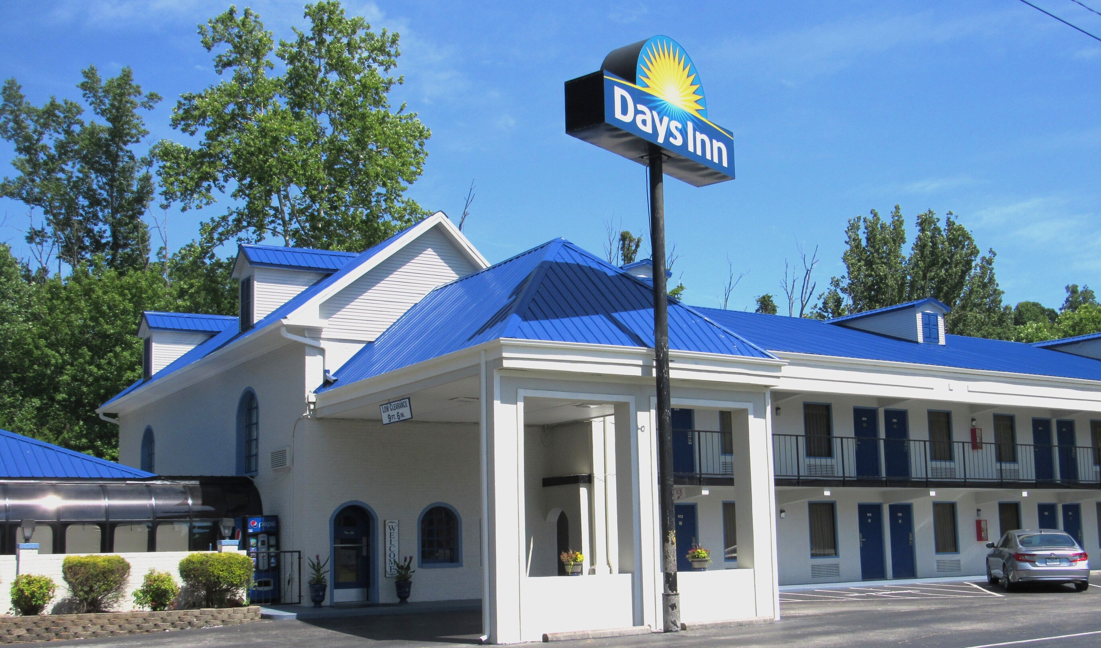 Um Days Inn com teto azul, um letreiro convidativo e um aviso de altura restrita.
