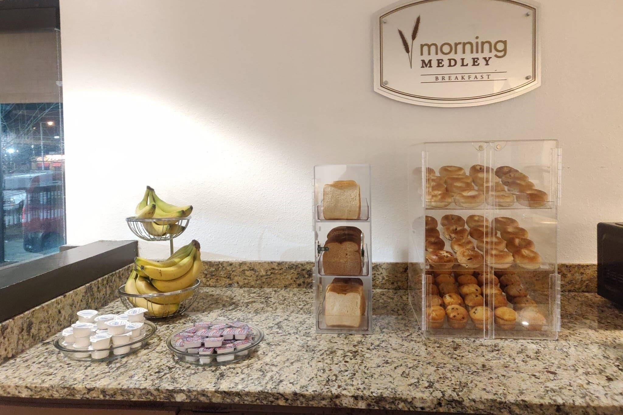 Um buffet de café da manhã com pães, doces e bananas sobre um balcão de granito.