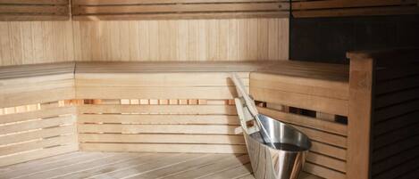 Uma sauna com bancos de madeira e um balde de metal.