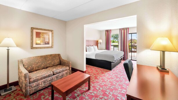 Quarto de hotel com sofá, cama, mesa e abajur.