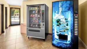 Máquina automática de vendas e bebedouro em um corredor.