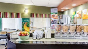 Uma área de refeições com uma cesta de frutas, papel toalha e dispensadores de cereais.