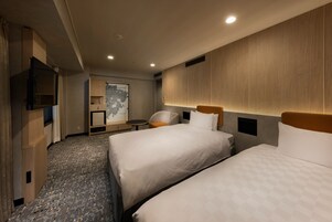 Quarto de hotel com duas camas, uma mesa pequena, uma cadeira, uma televisão e um mapa na parede.