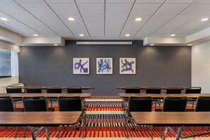 Uma sala de conferências com uma mesa comprida, cadeiras e três quadros abstratos na parede.