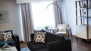 Uma sala de estar moderna com um sofá, poltronas, uma mesa de centro e uma estante.