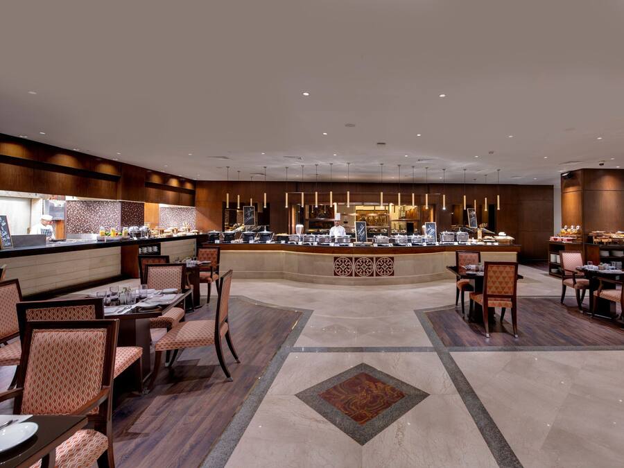 Um hall de hotel moderno com área de bar central, espaços de assento e design de piso padronizado.