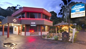 Um motel com fachada vermelha e branca, uma receção e uma entrada bem iluminada.