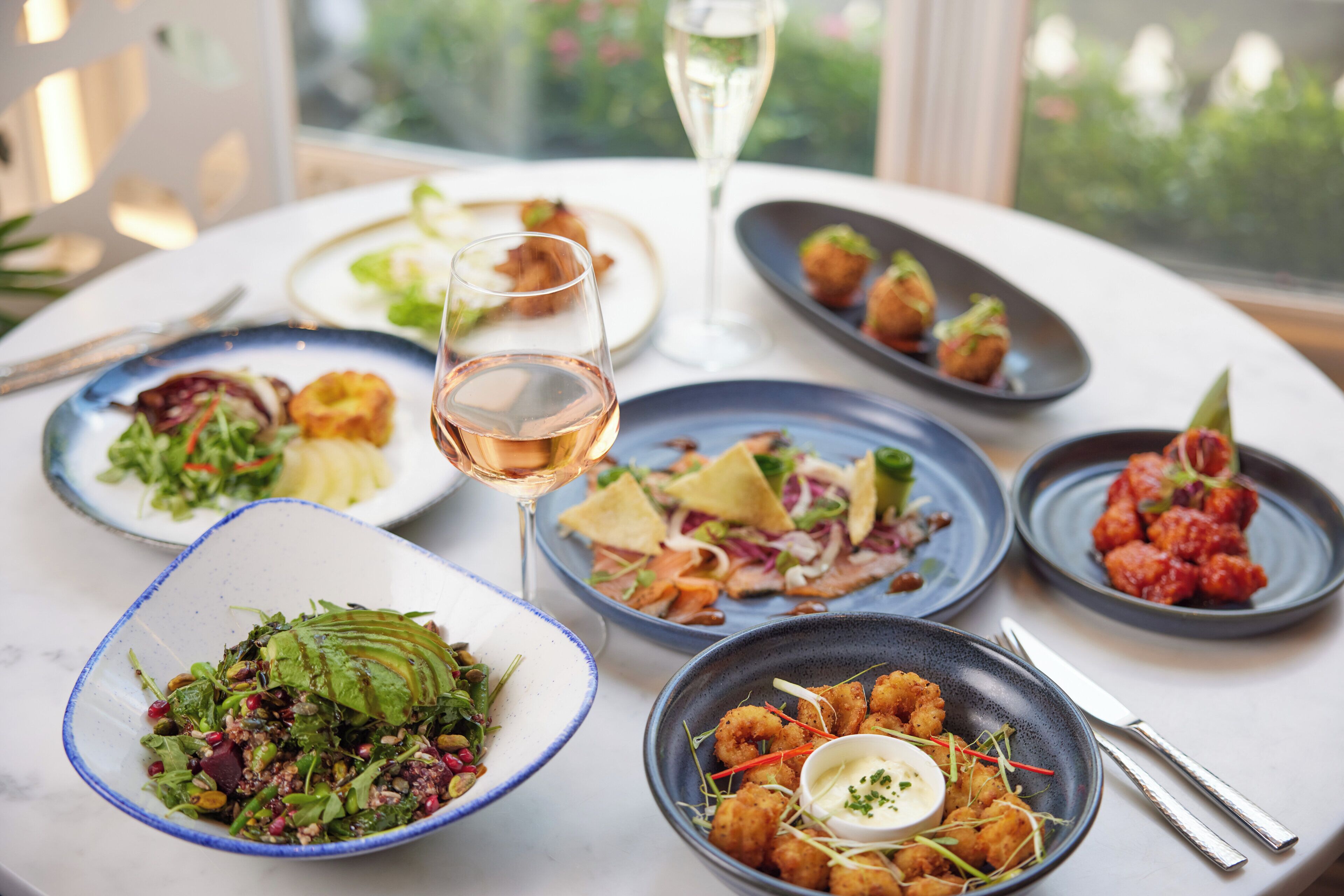 Uma mesa com diversos pratos e um copo de vinho, sugerindo um ambiente de refeição.