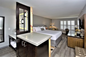 Quarto de hotel moderno com cama, escrivaninha, espelho e janela com persianas.