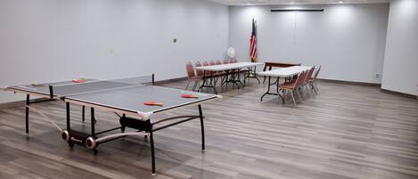 Sala de conferências com mesas de pingue-pongue, cadeiras e uma bandeira americana.