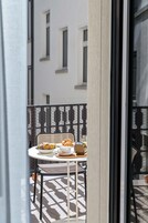 Varanda com uma mesa posta para o café da manhã, incluindo croissants e uma cafeteira.