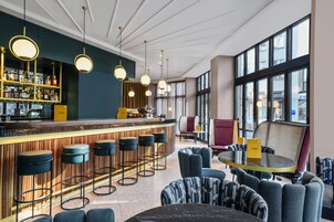 Uma área de bar com banquetas, balcão e um espaço para sentar com cadeiras e uma mesa.