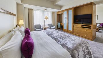 Quarto de hotel com uma cama grande, televisão, escrivaninha e guarda-roupa.