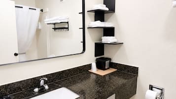 Casa de banho com lavatório, espelho, suportes para toalhas e rolo de papel higiénico.