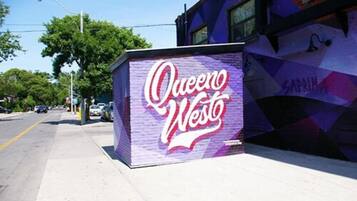 Um edifício com uma placa roxa e branca com a inscrição 'Queen West'.