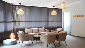 Uma área de estar moderna com um conjunto de sofás, cadeiras de vime e iluminação pendente.