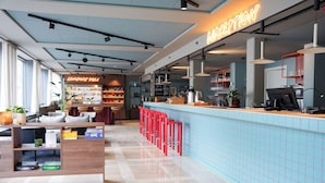 Uma área de bar moderna com um letreiro de neon, um balcão e banquetas vermelhas.