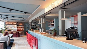 Uma área de bar moderna com um letreiro de neon, banquetas, um balcão e um espaço de estar com sofá e cadeiras.