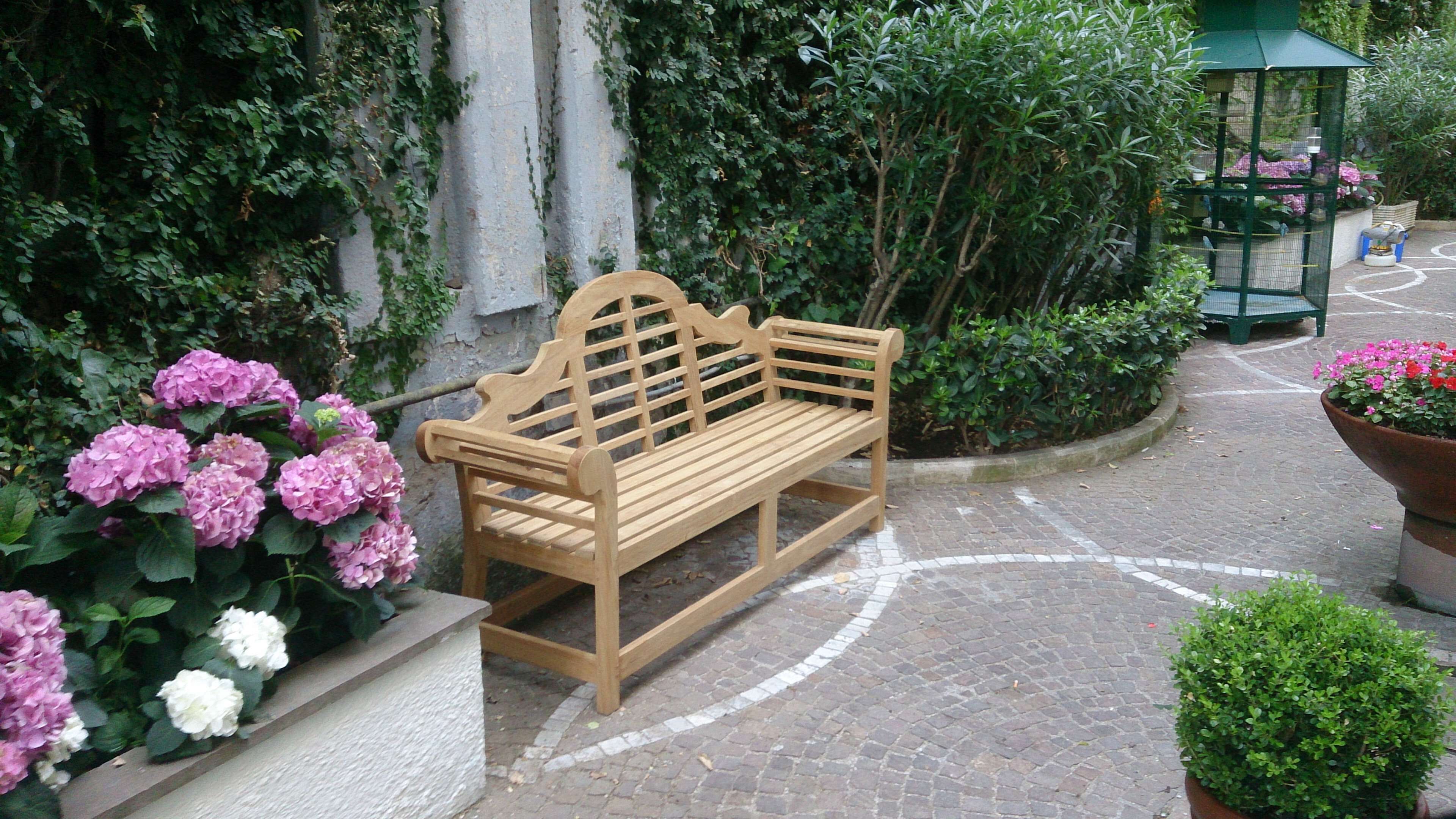 Um banco de madeira em área de jardim com vasos de plantas e um muro de pedra.