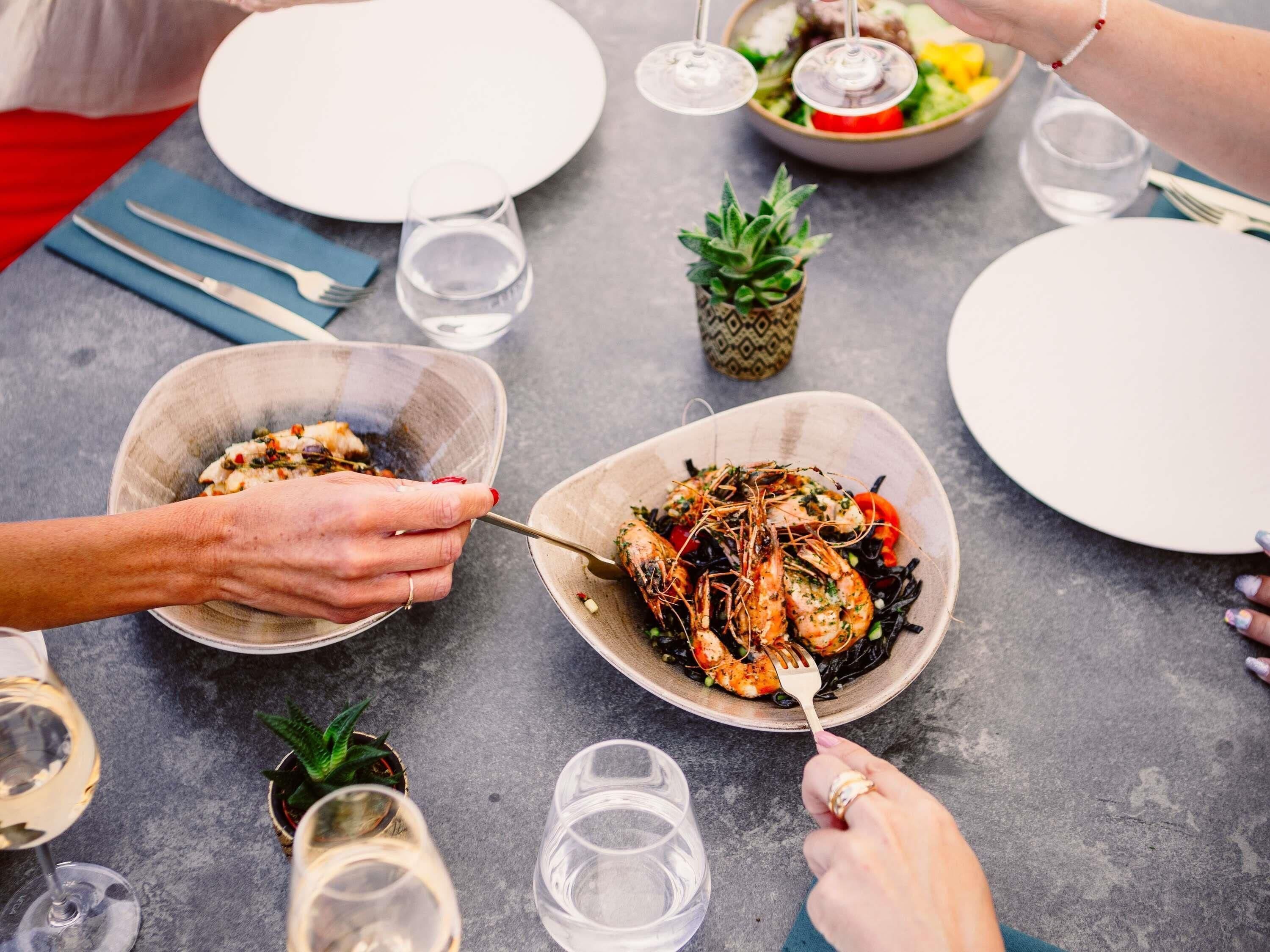 Uma mesa de jantar com pratos, copos e um pequeno vaso de planta.
