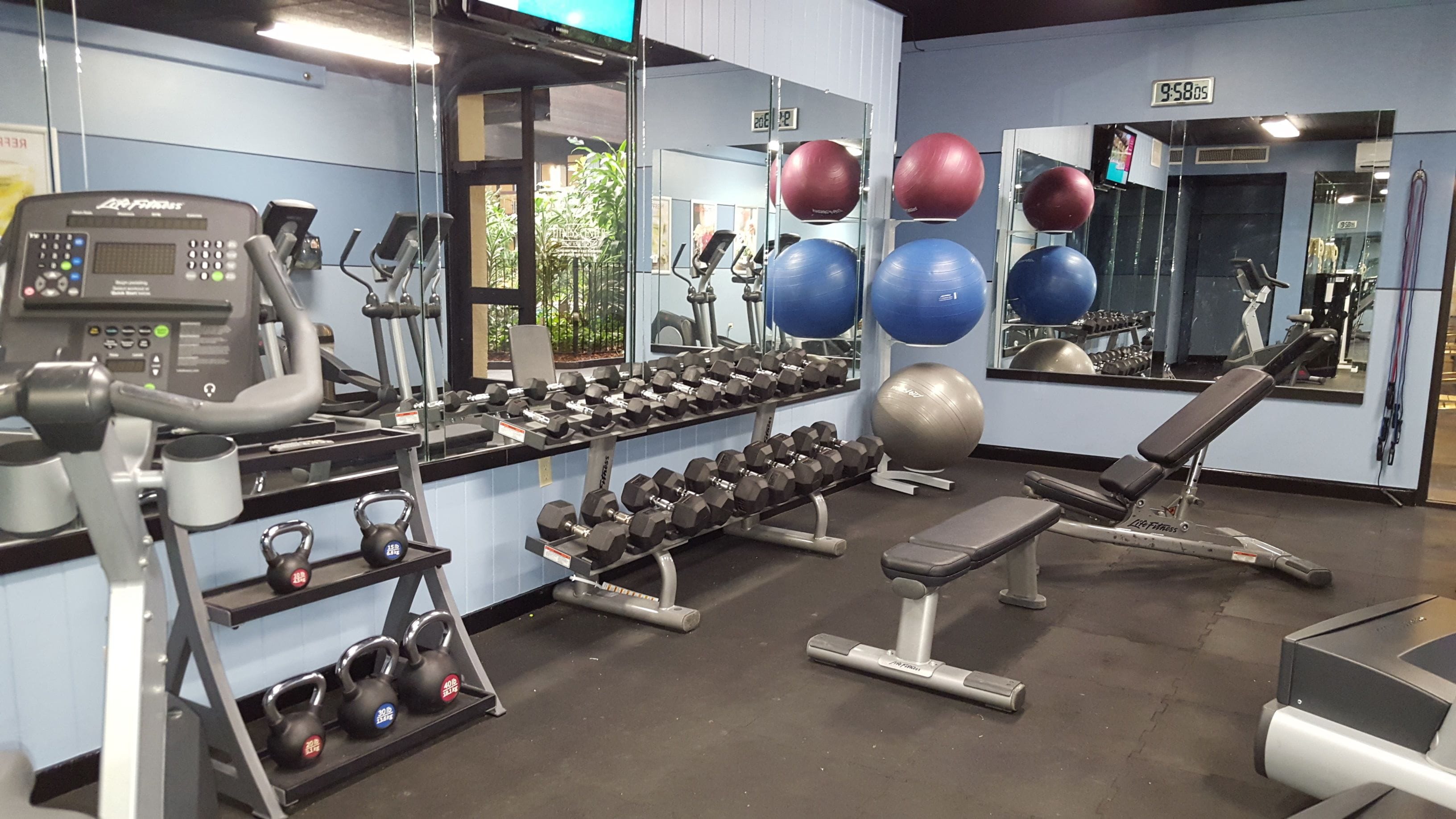 Uma academia com equipamentos de ginástica, incluindo esteiras, halteres e bolas de exercício.