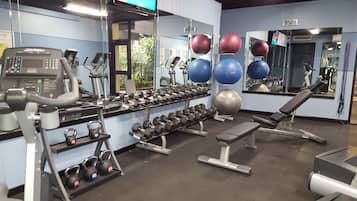 Uma academia com equipamentos de ginástica, incluindo esteiras, halteres e bolas de exercício.