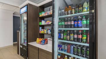 Quarto de hotel com minibar repleto de lanches, bebidas e frigorífico.