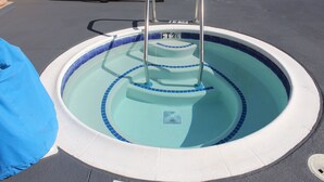 Uma pequena piscina redonda com borda em azulejos azuis e escada de metal.