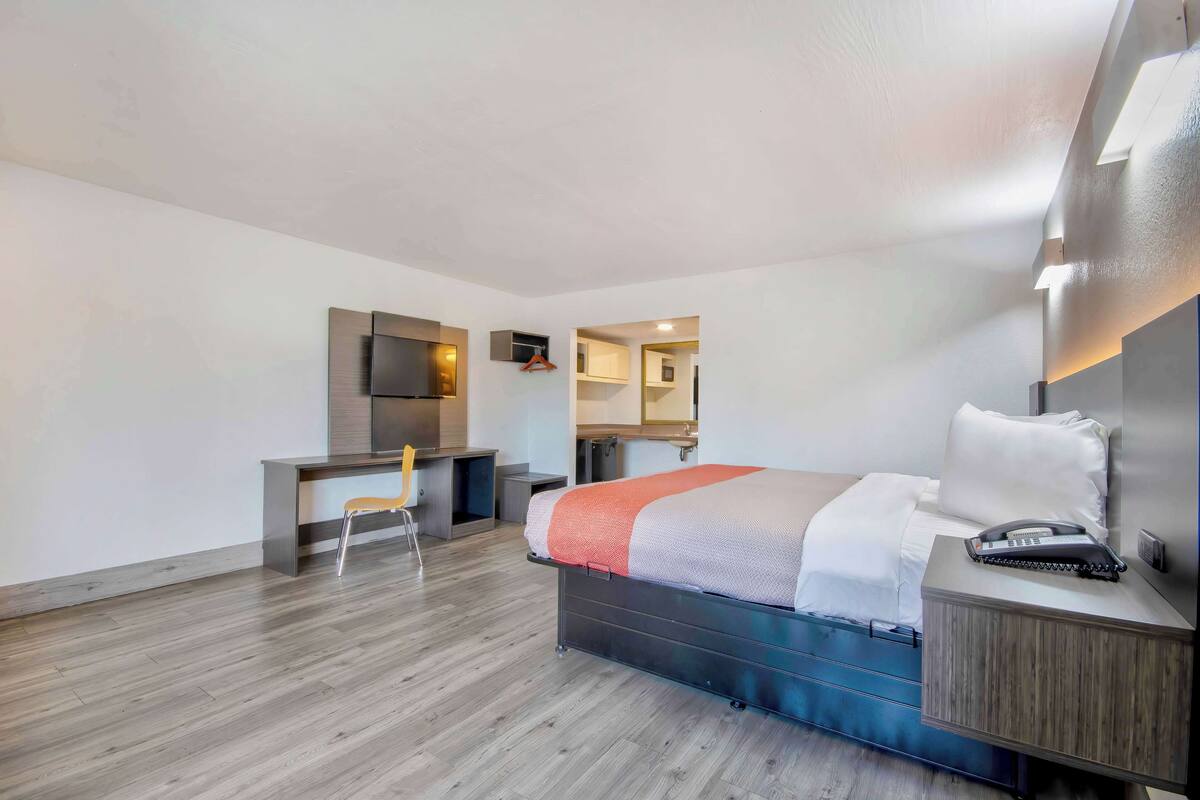 Quarto de hotel moderno com cama, escrivaninha e cadeira.
